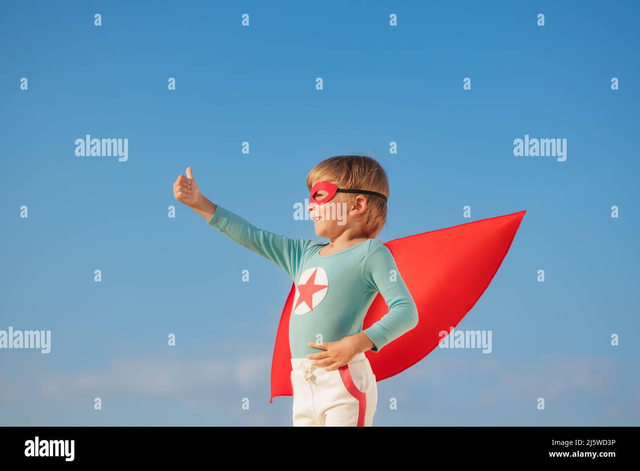 Superhero child playing outdoor. Super hero kid against blue summer sky ...