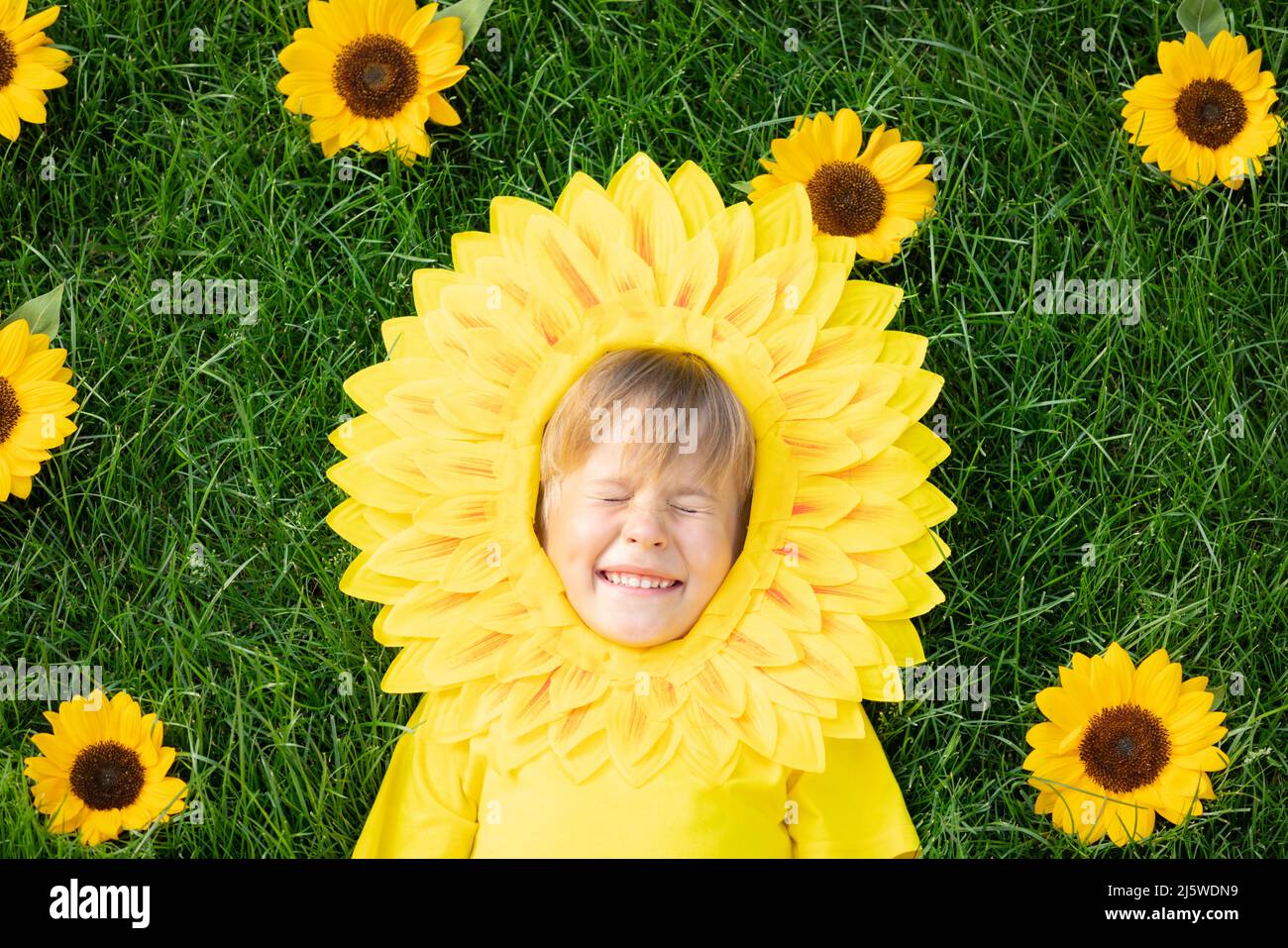 Happy child playing outdoor in spring park. Kid lying on green grass ...