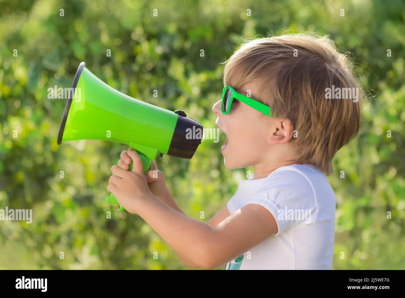 Happy child shouting through loudspeaker. Portrait of kid outdoor. Boy ...