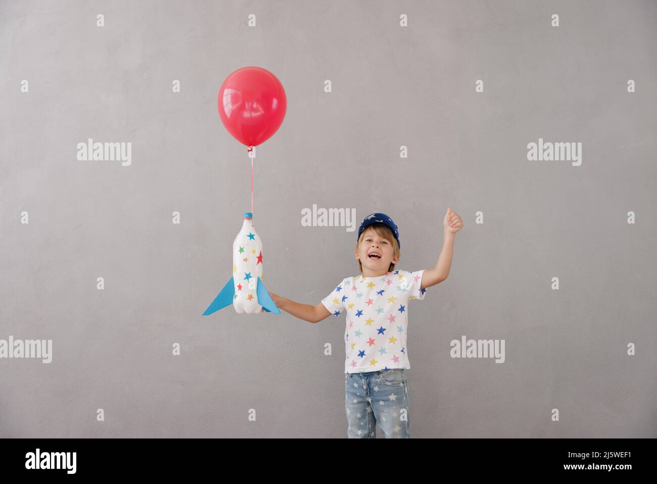 Happy child playing with toy rocket at home. Kid pretend to be ...