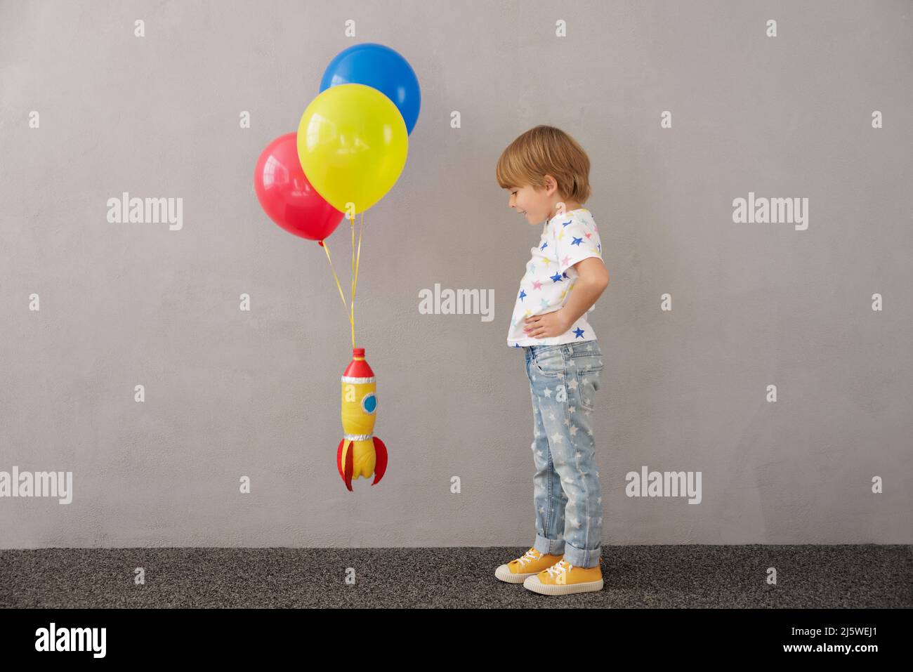 Happy child playing with toy rocket at home. Kid pretend to be ...