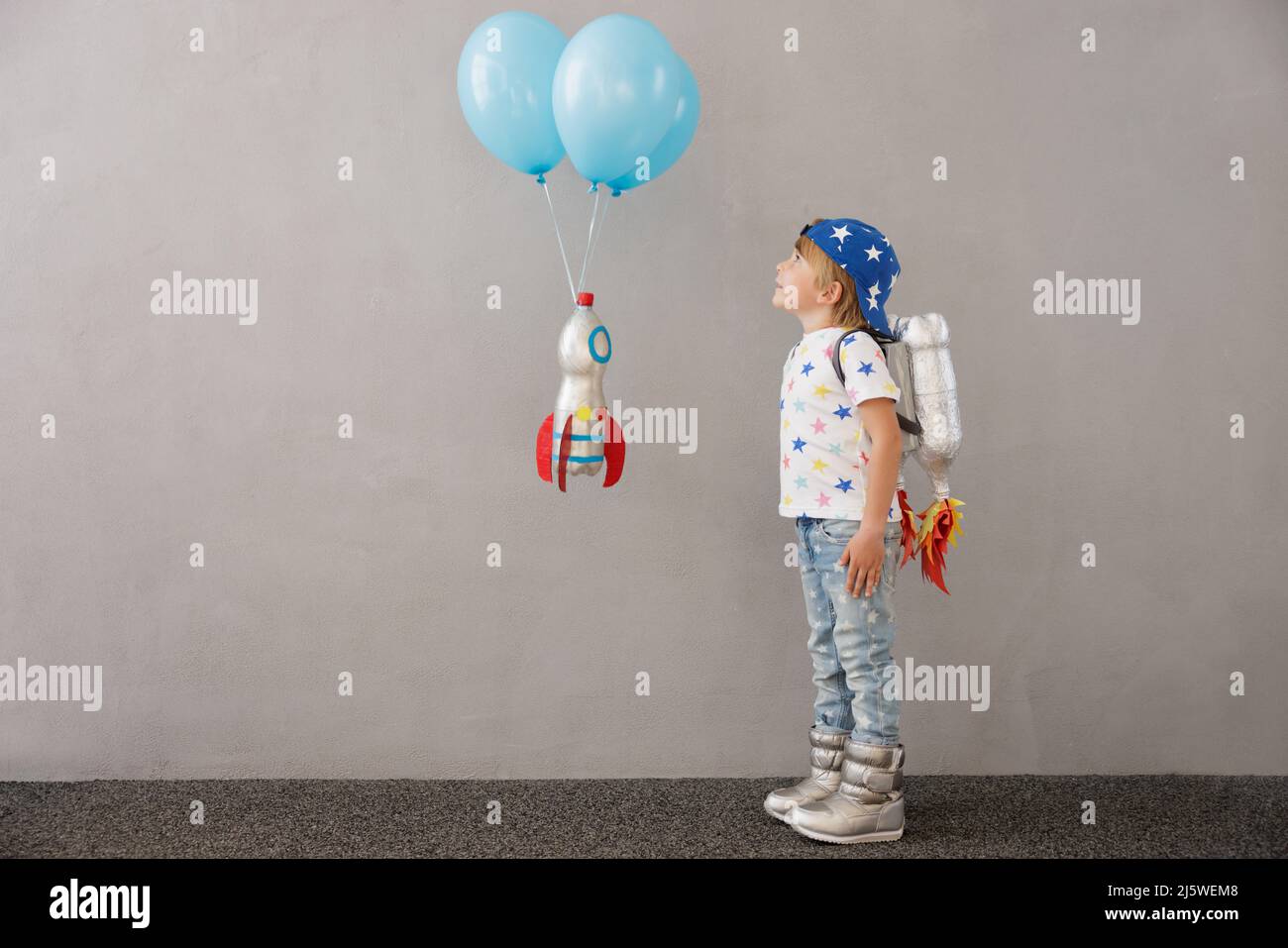 Happy child playing with toy rocket at home. Kid pretend to be ...