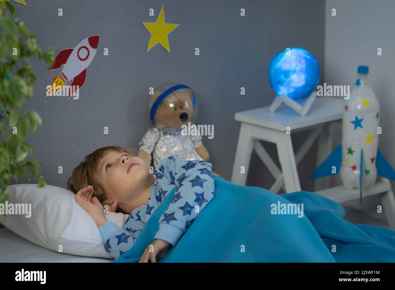 Happy child sleeping with toy rocket and teddy bear. Kid pretend to be ...