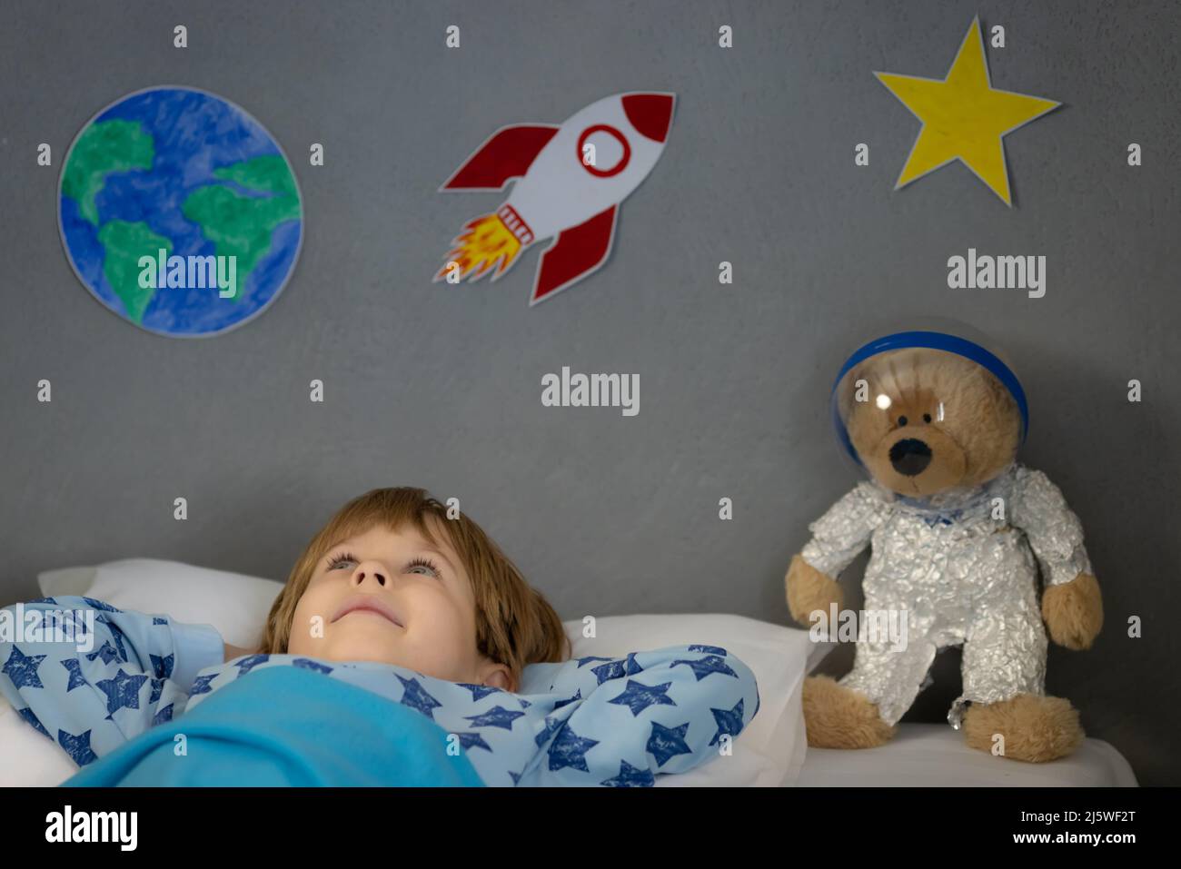 Happy child sleeping with toy rocket and teddy bear. Kid pretend to be ...