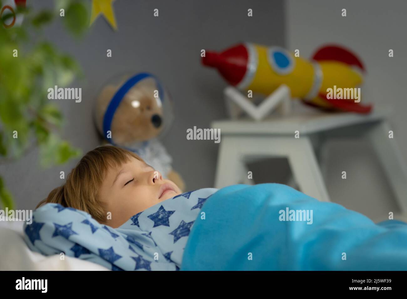 Happy child sleeping with toy rocket and teddy bear. Kid pretend to be ...