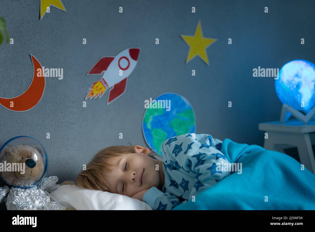 Happy child sleeping with toy rocket and teddy bear. Kid pretend to be ...