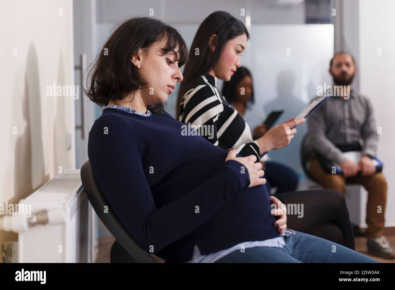 Pregnant job recruiter holding hand on belly waiting in startup ...