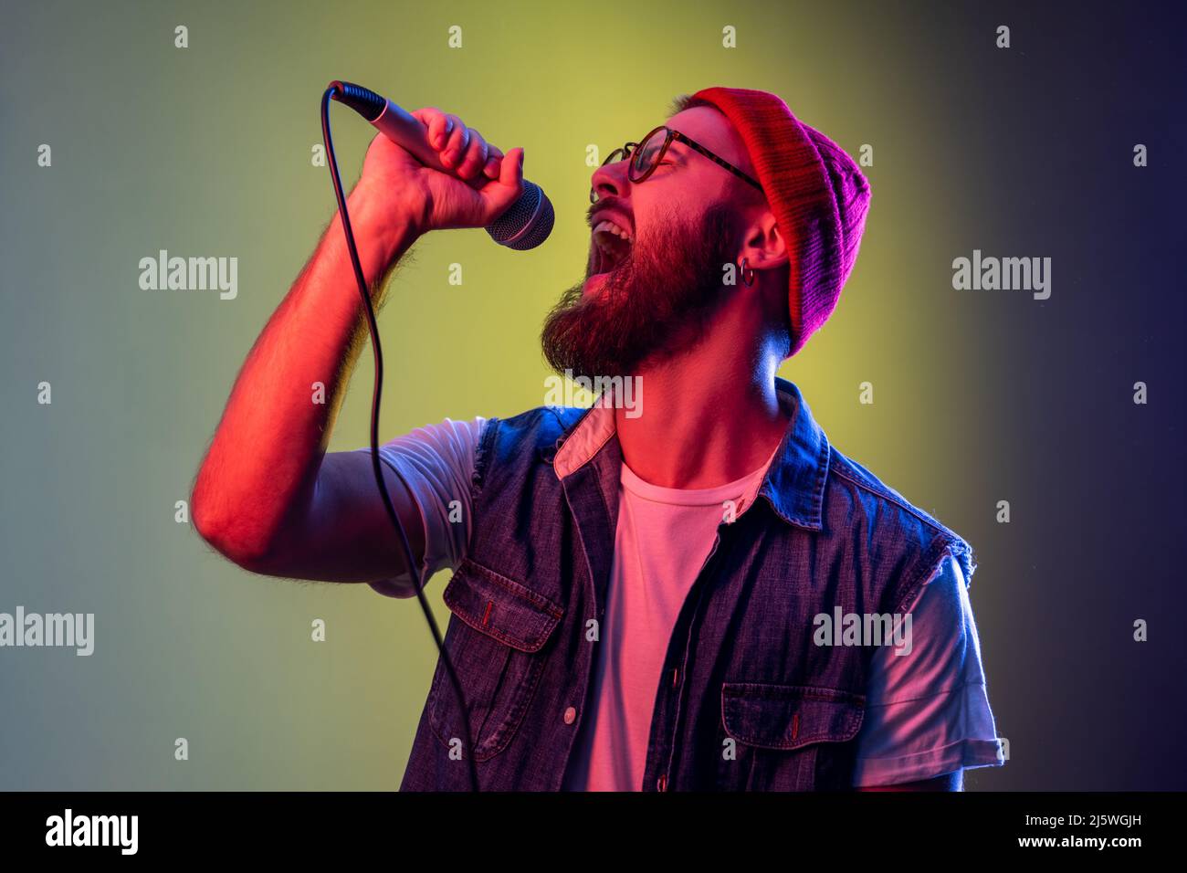 Bearded hipster man loudly singing song holding microphone in hand ...