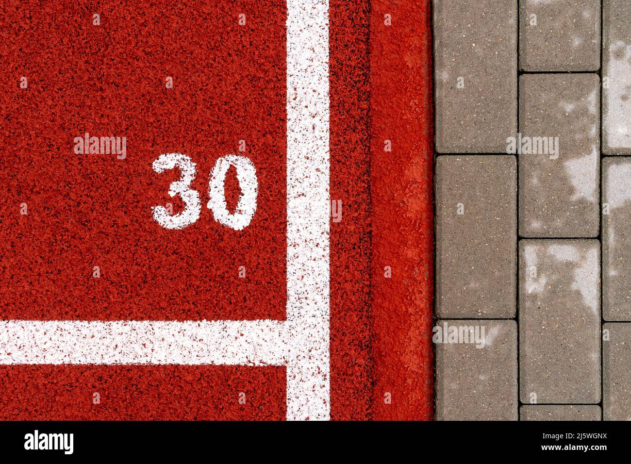 Sidewalk near the rubber running track with 30m mark Stock Photo - Alamy