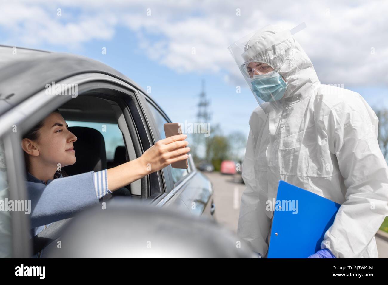 woman in car showing phohe to healthcare worker Stock Photo - Alamy