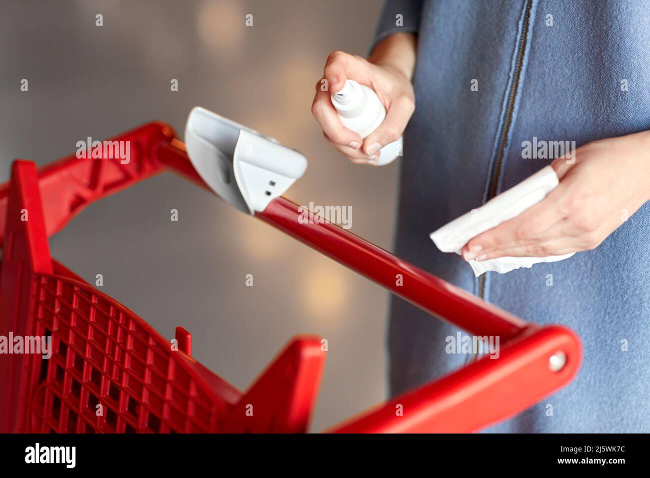 woman cleaning shopping cart handle with sanitizer Stock Photo - Alamy