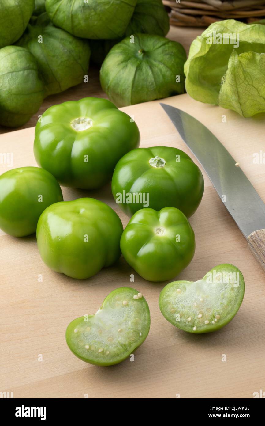 Fresh green whole and halved Mexican tomatillo on a cutting board Stock ...