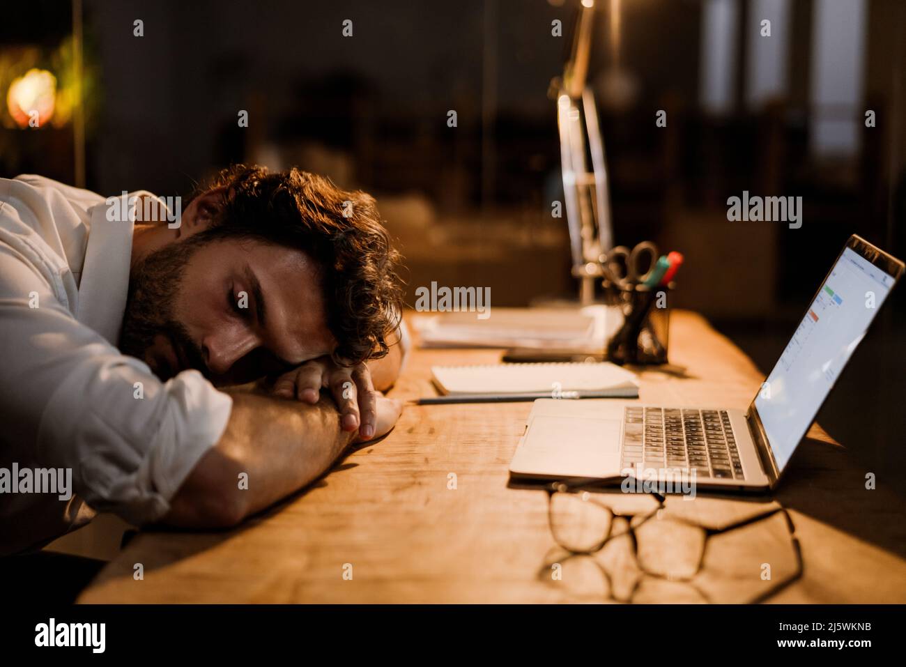 White bearded man sleeping while working with laptop in evening at ...