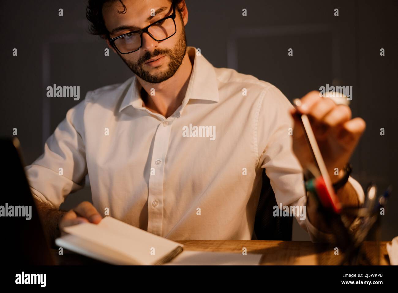White bearded man writing down notes in planner while working at office ...