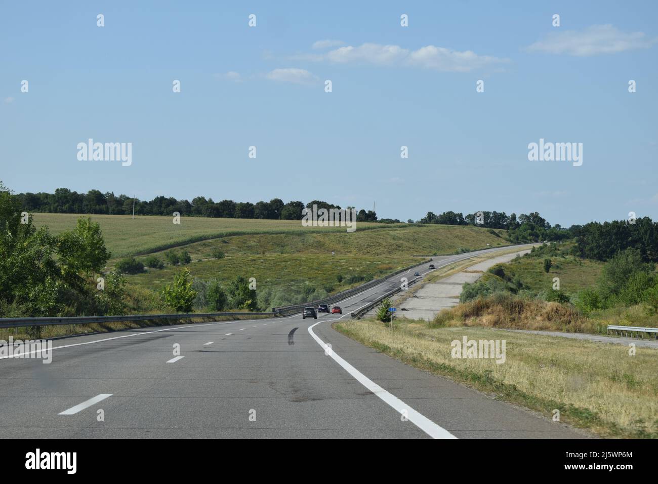 Cars drive on the highway, the road outside the city among the fields ...