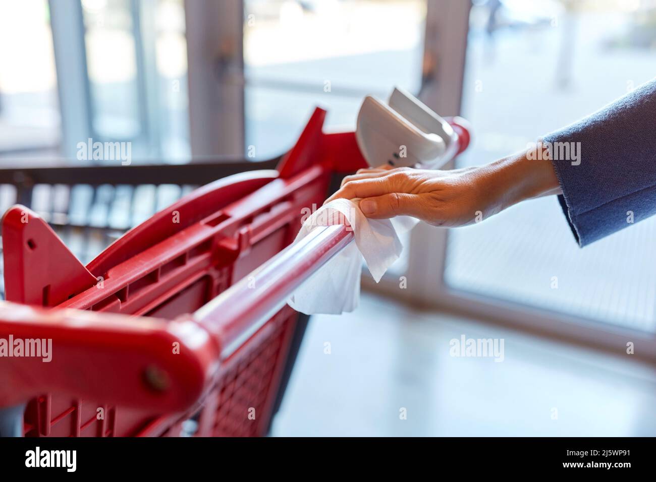 hand cleaning shopping cart handle with wet wipe Stock Photo - Alamy