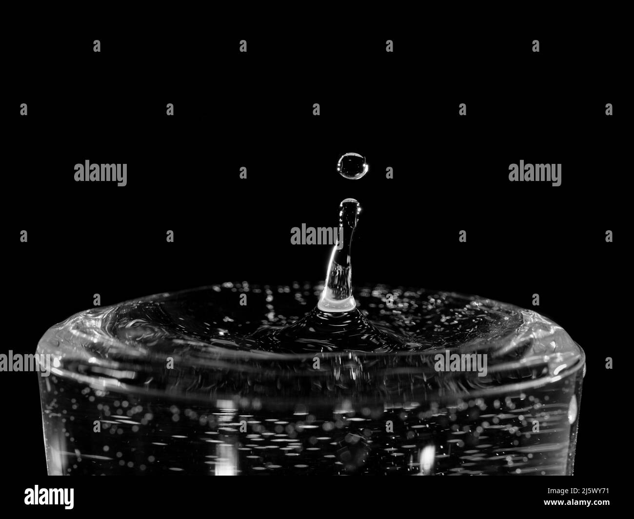 Closeup of a single water droplet hitting the surface, black and white ...