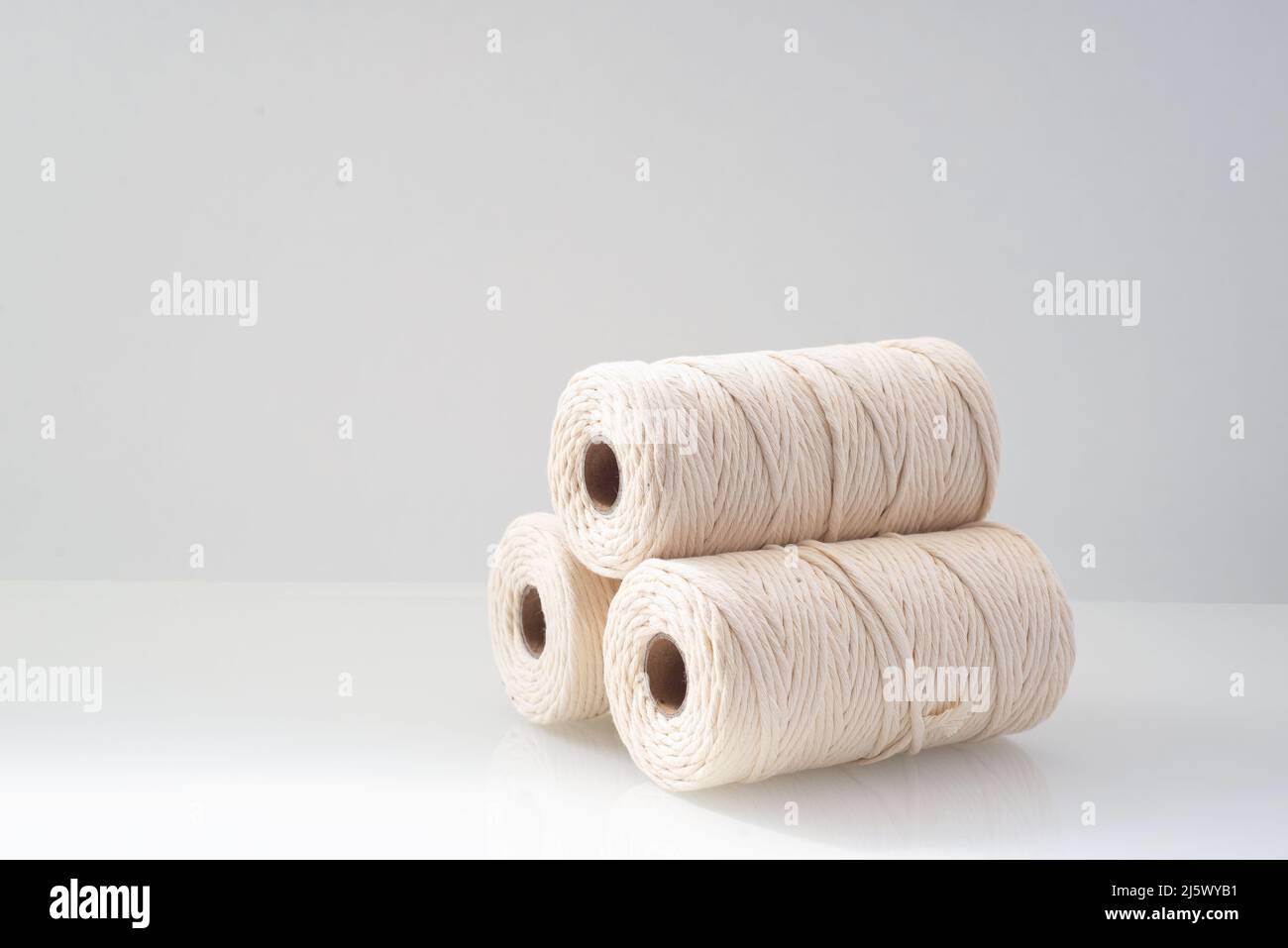 macrame threads wound bobbins of natural beige color are located on a ...