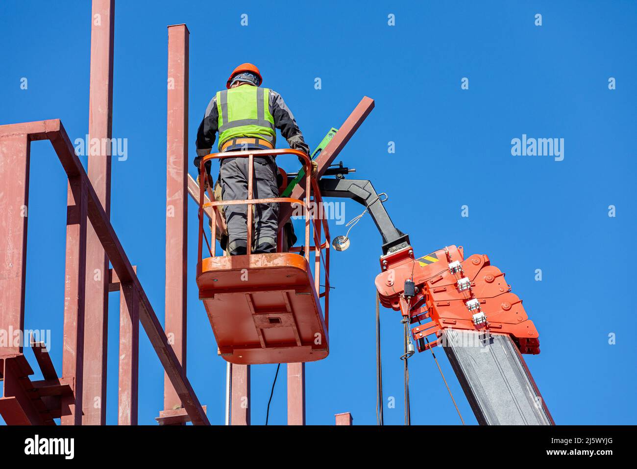 Male builders work at height in a lifting cradle, creating the iron ...