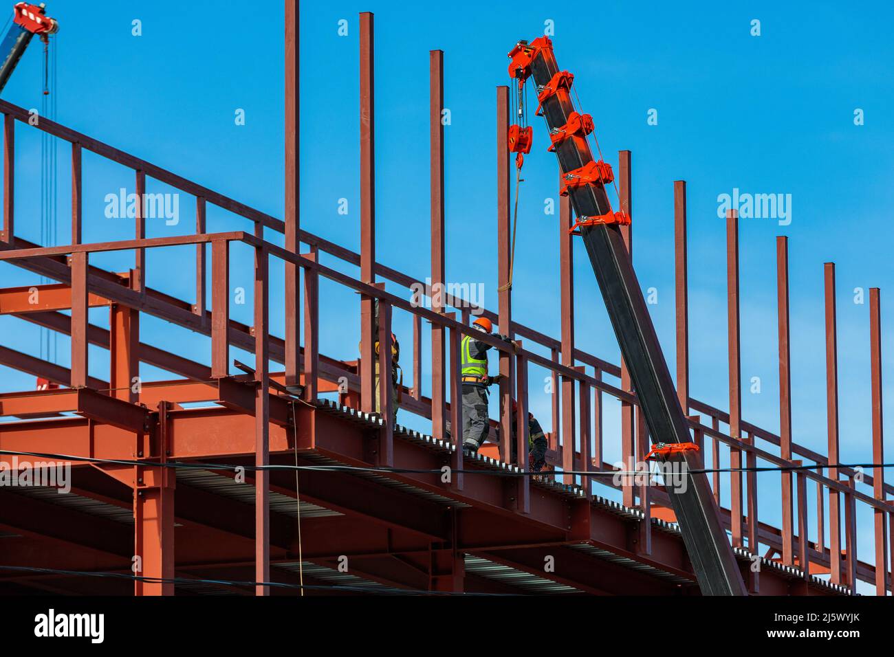 Builders fix iron beams with a crane. Frame construction Stock Photo ...