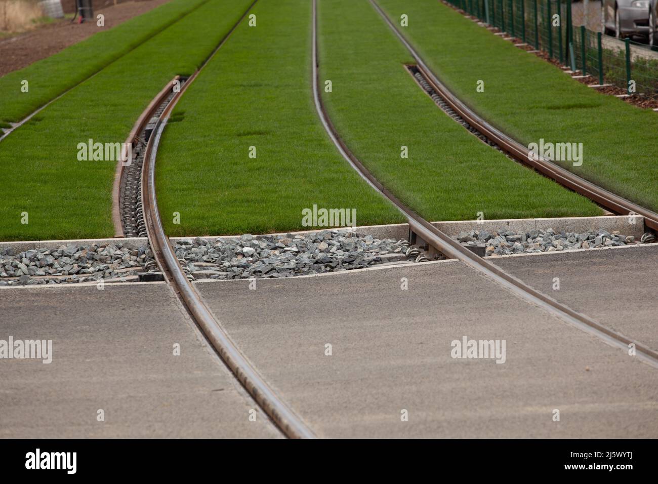 The rails pass on the road then stone to finish on green grass guiding ...