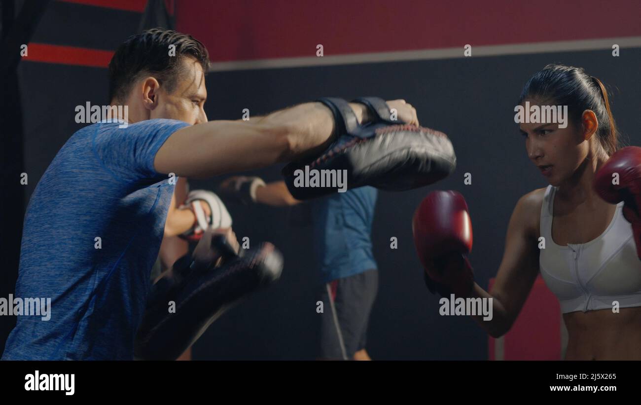 Asian beautiful young woman exercise with trainer at boxing gloves and ...