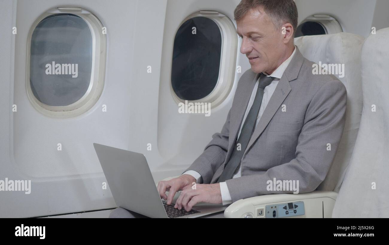 Senior business people man in first class airline working on his laptop ...