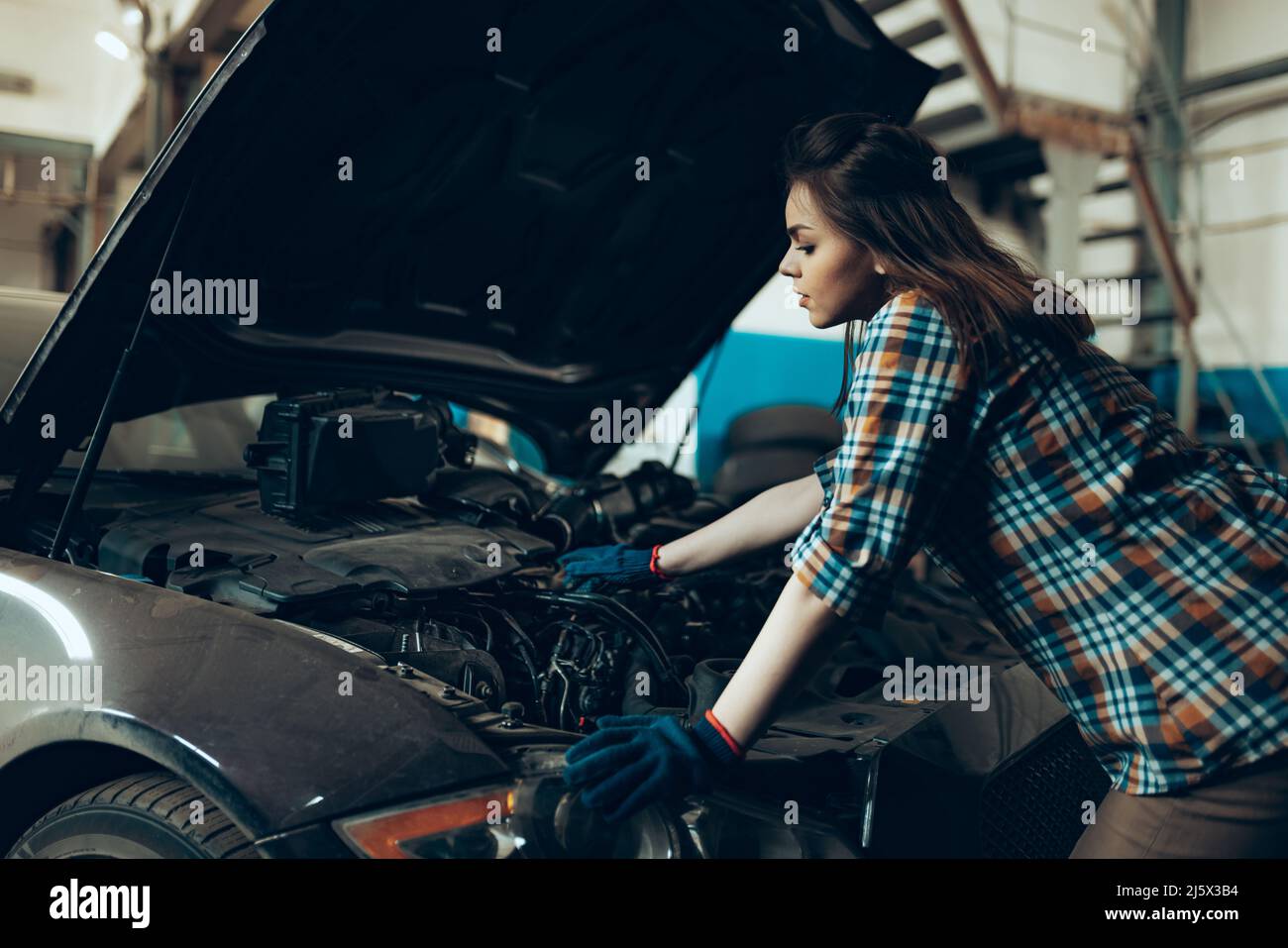 Female auto mechanic, beautiful young girl in working process at auto service station, indoors ...