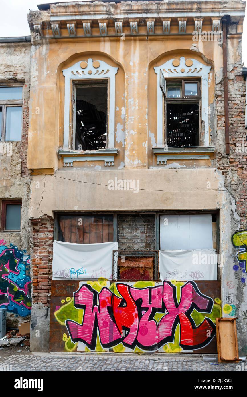 Run down side street with graffiti on walls of crumbling buildings in ...