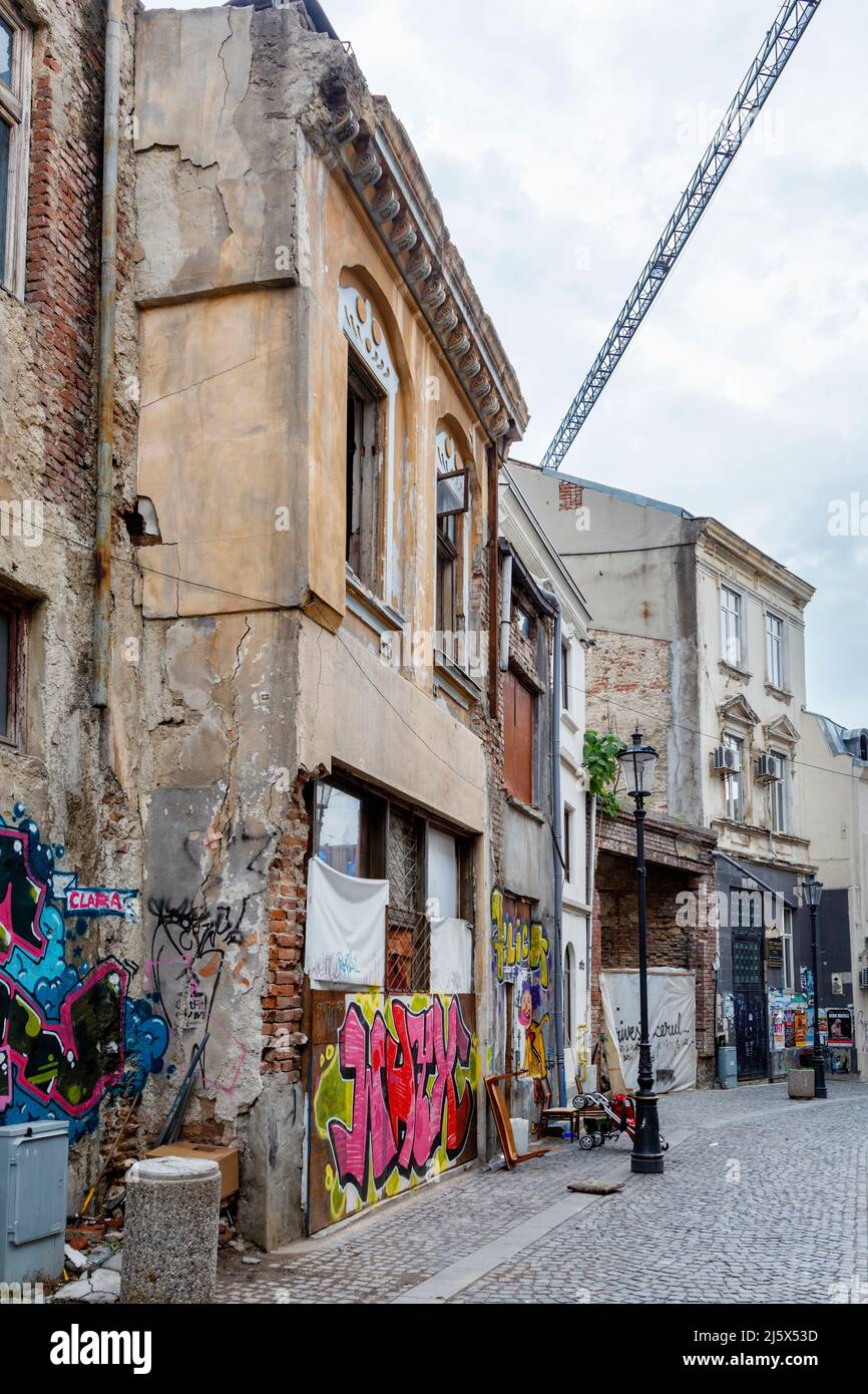Run down side street with graffiti on walls of crumbling buildings in ...