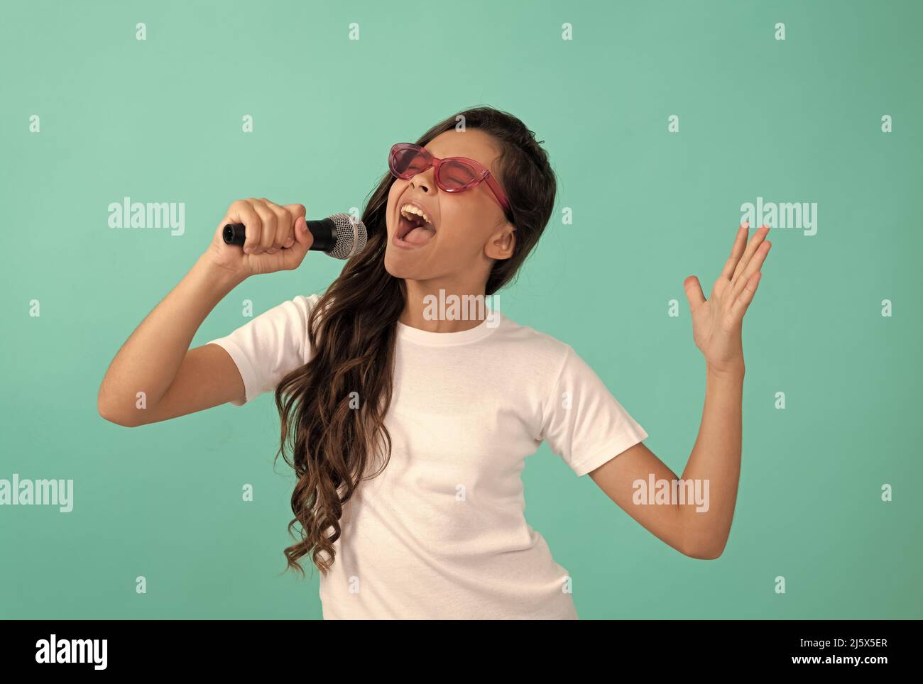 Happy kid singer sing karaoke song to microphone blue background, music ...
