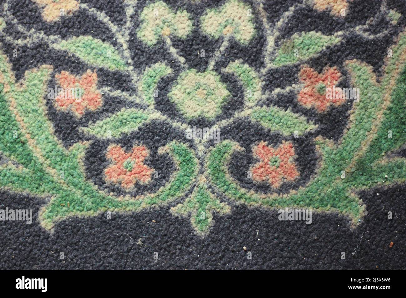 A vintage carpet with a floral motif with orange and green plants ...