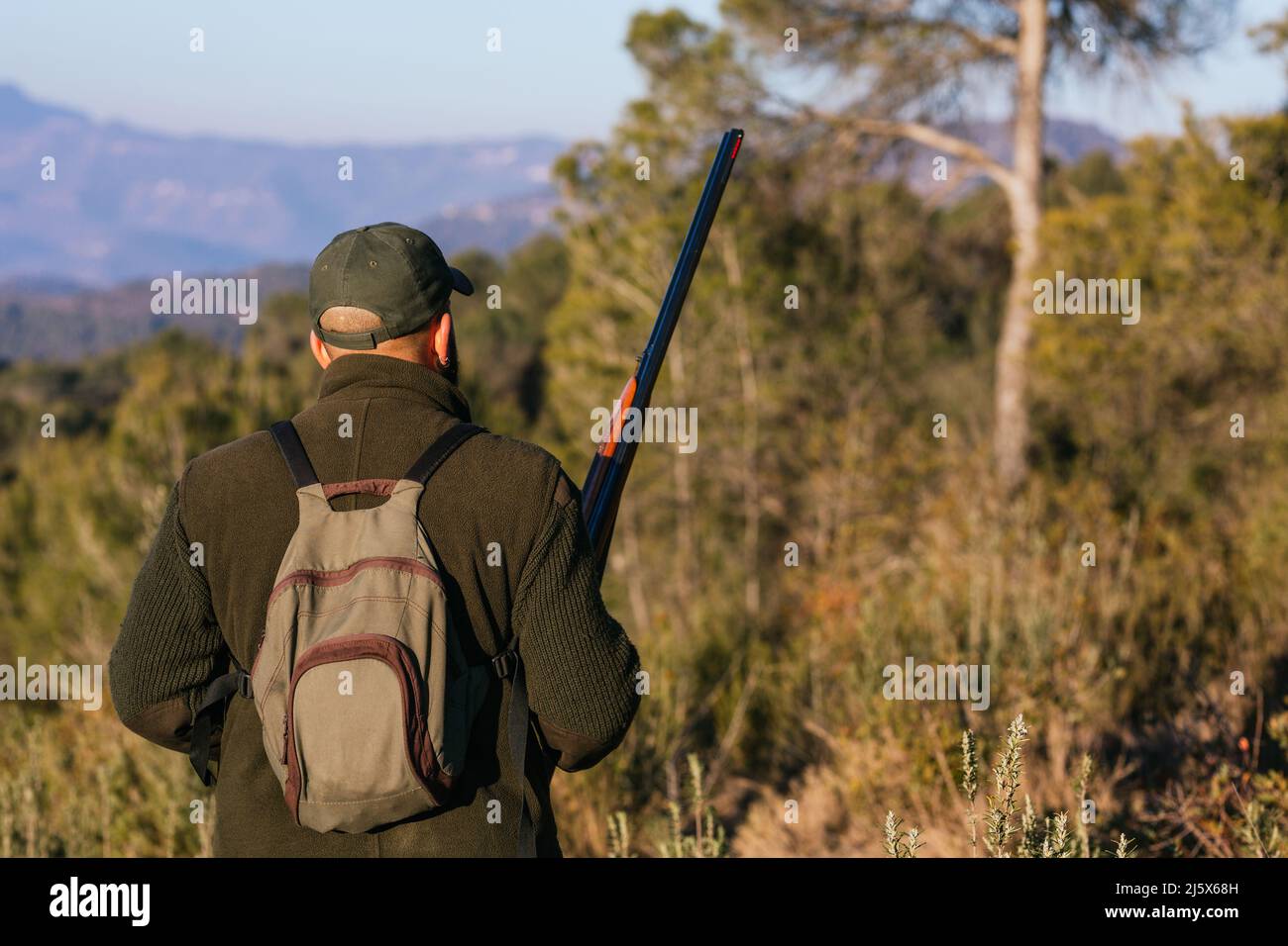 Hunter on his back with his gun up walking in nature Stock Photo - Alamy