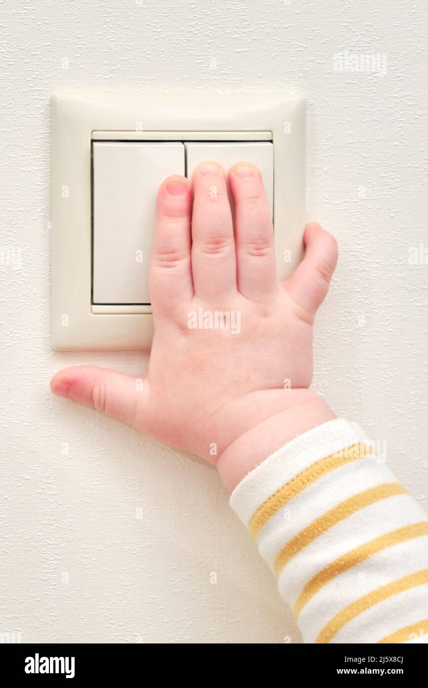 Toddler baby boy turns the light on and off with an electric switch ...