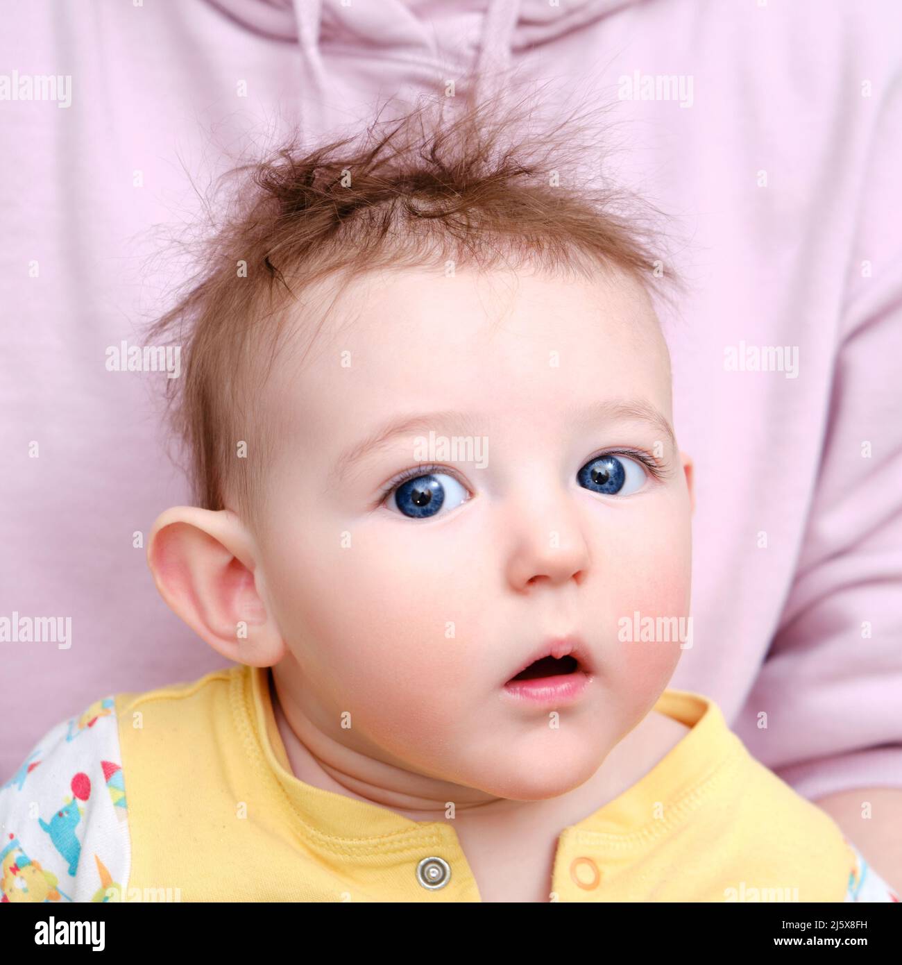Surprised infant baby boy with big blue eyes and disheveled hair in his ...