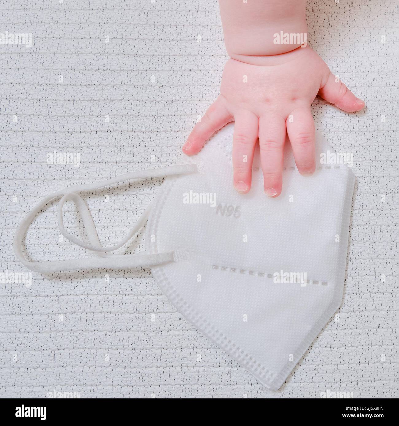 Baby hand and medical mask n95, close-up. Children fingers and an ...