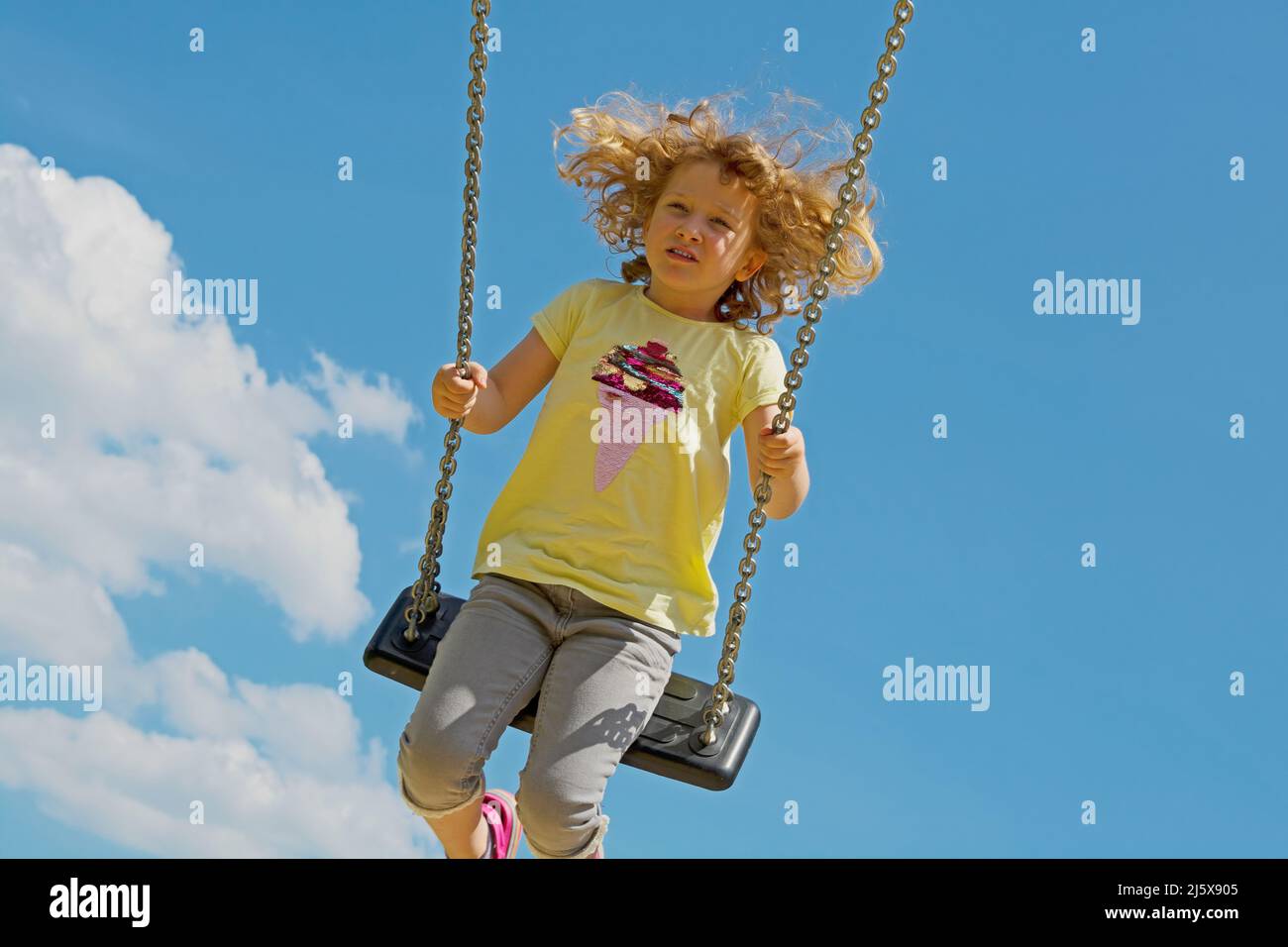 Child swings high. With blue sky background Stock Photo - Alamy