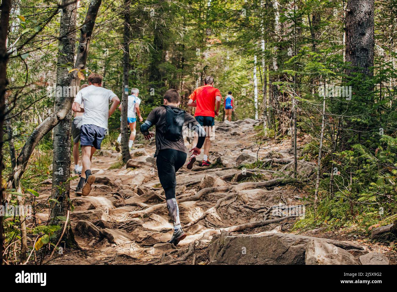 group men run marathon uphill over rocks and roots Stock Photo - Alamy
