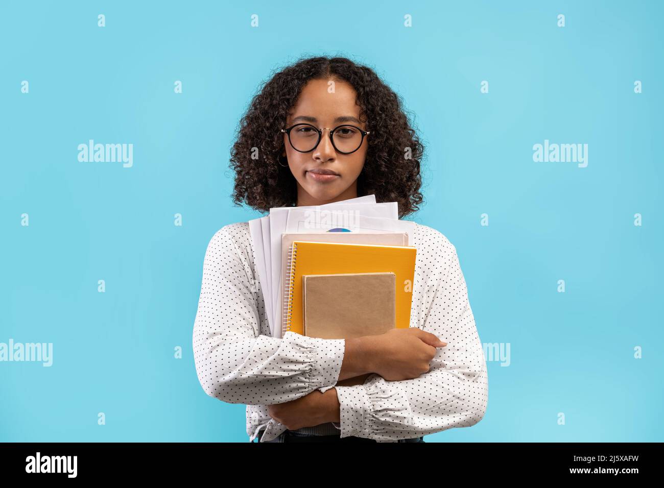 Doubtful young black female student with notebooks and papers looking ...