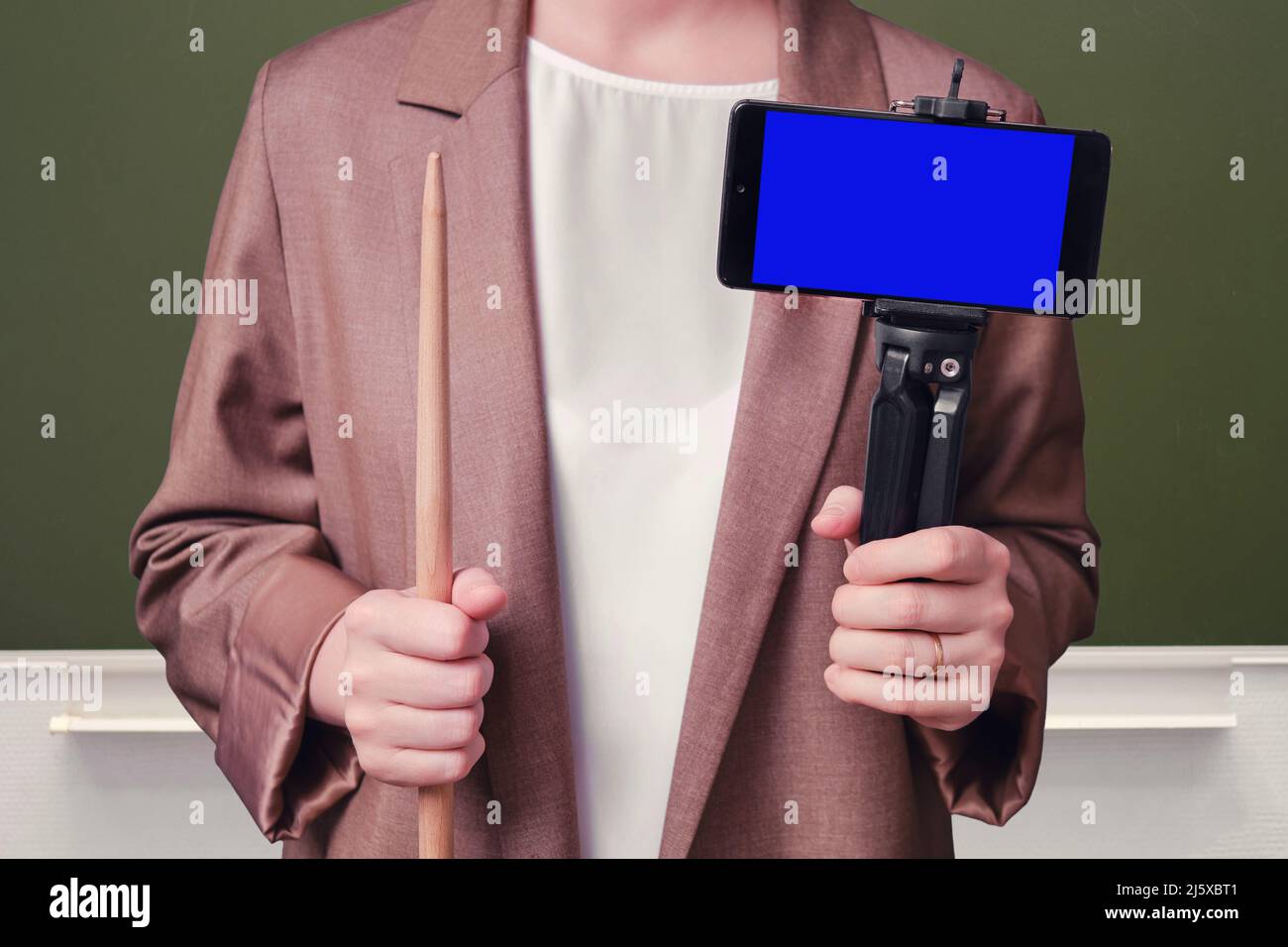Woman teacher with phone for online lesson on school blackboard in the ...