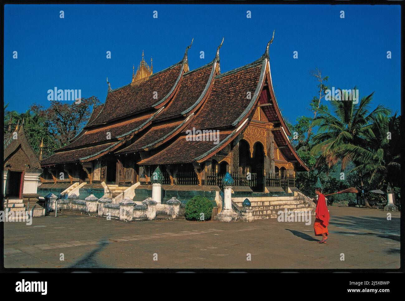 A Buddhist monk cleans the temple grounds in the early morning, Wat ...