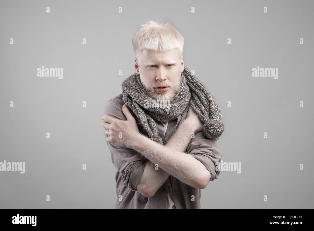 Sick albino guy with scarf around his neck, feeling cold while standing ...