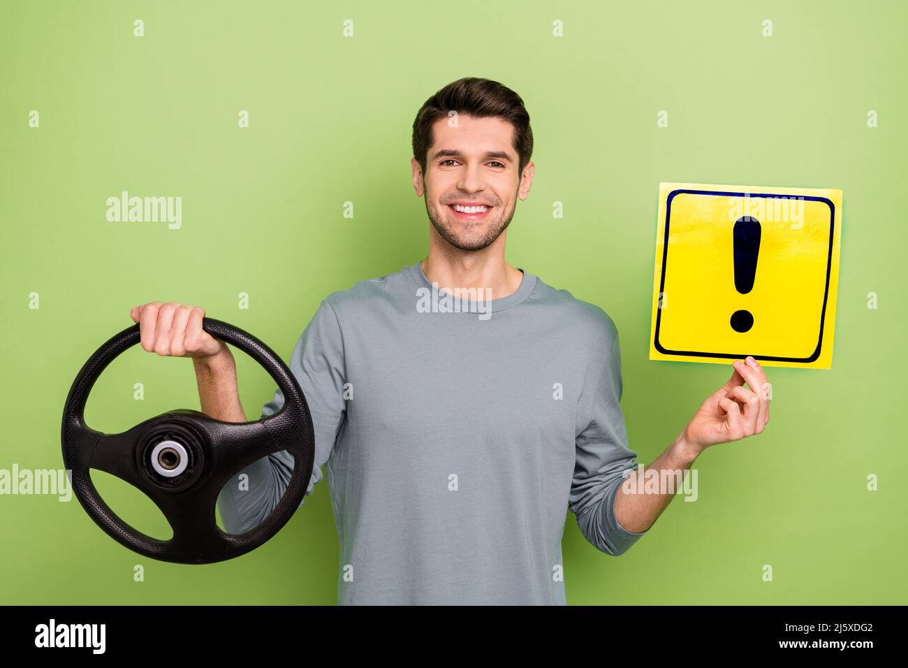 Photo of optimistic millennial brunet guy drive car hold sign wear ...