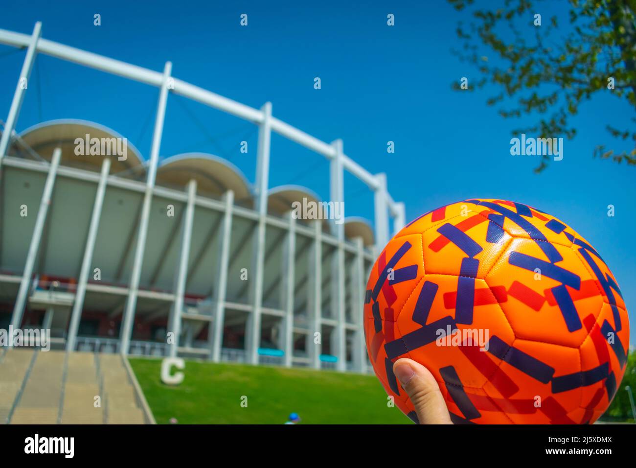 Hand holding Colorful Football with football stadium background Qatar ...
