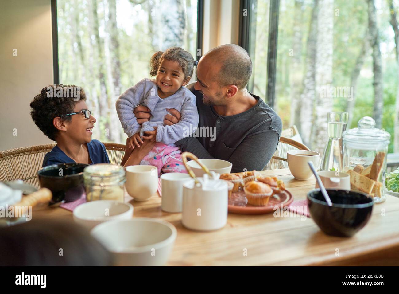 Happy father and kids eating at dining table Stock Photo - Alamy
