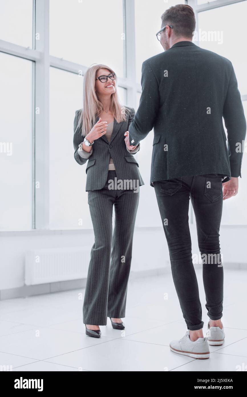 smiling employees discuss something standing in the office corridor ...