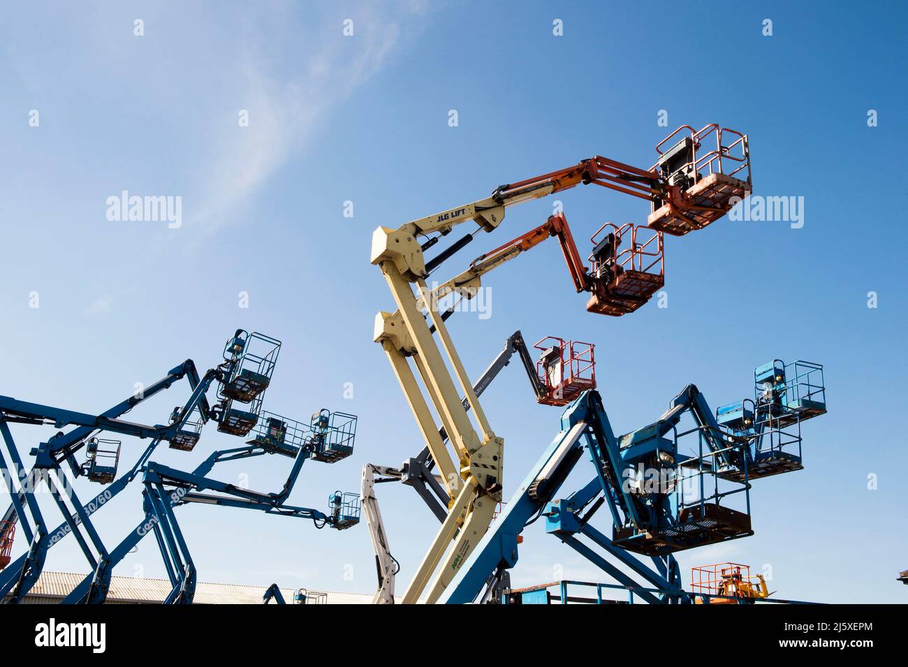 Cherry Pickers silhouetted agaianst a blue sky on an industrial estate ...