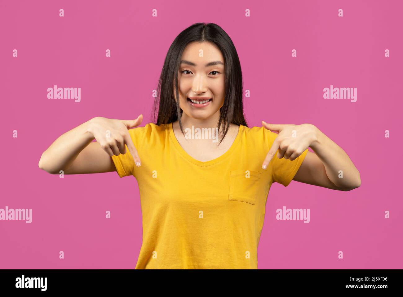 Happy korean lady pointing fingers down and smiling at camera, posing ...
