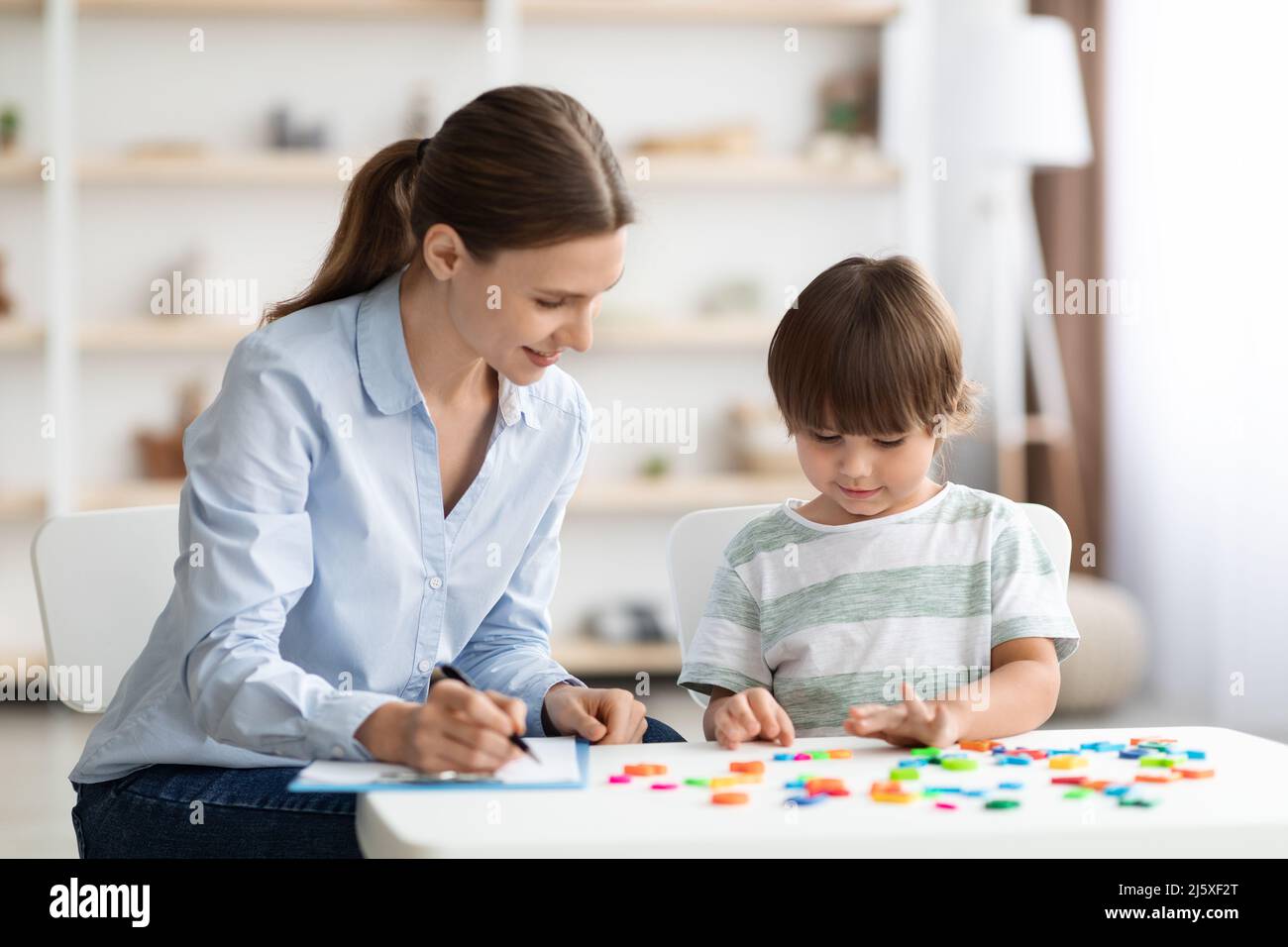 Cute little boy study to read with professional tutor, positive woman ...