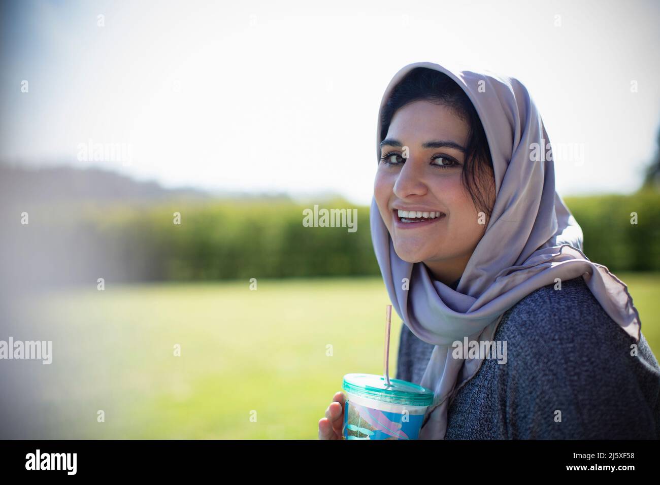 Portrait happy young Muslim woman in hijab drinking juice Stock Photo ...
